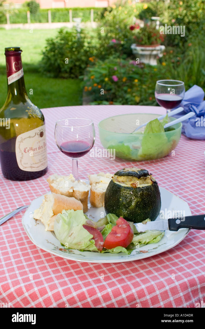 Meal with courgette and salad on table outside with garden visible in ...