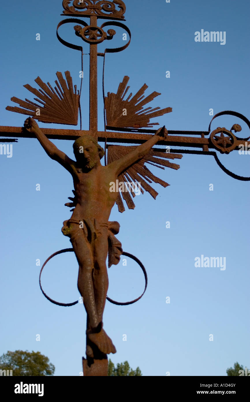 Corroded iron crucifix over grave in churchyard cemetry with figure of ...