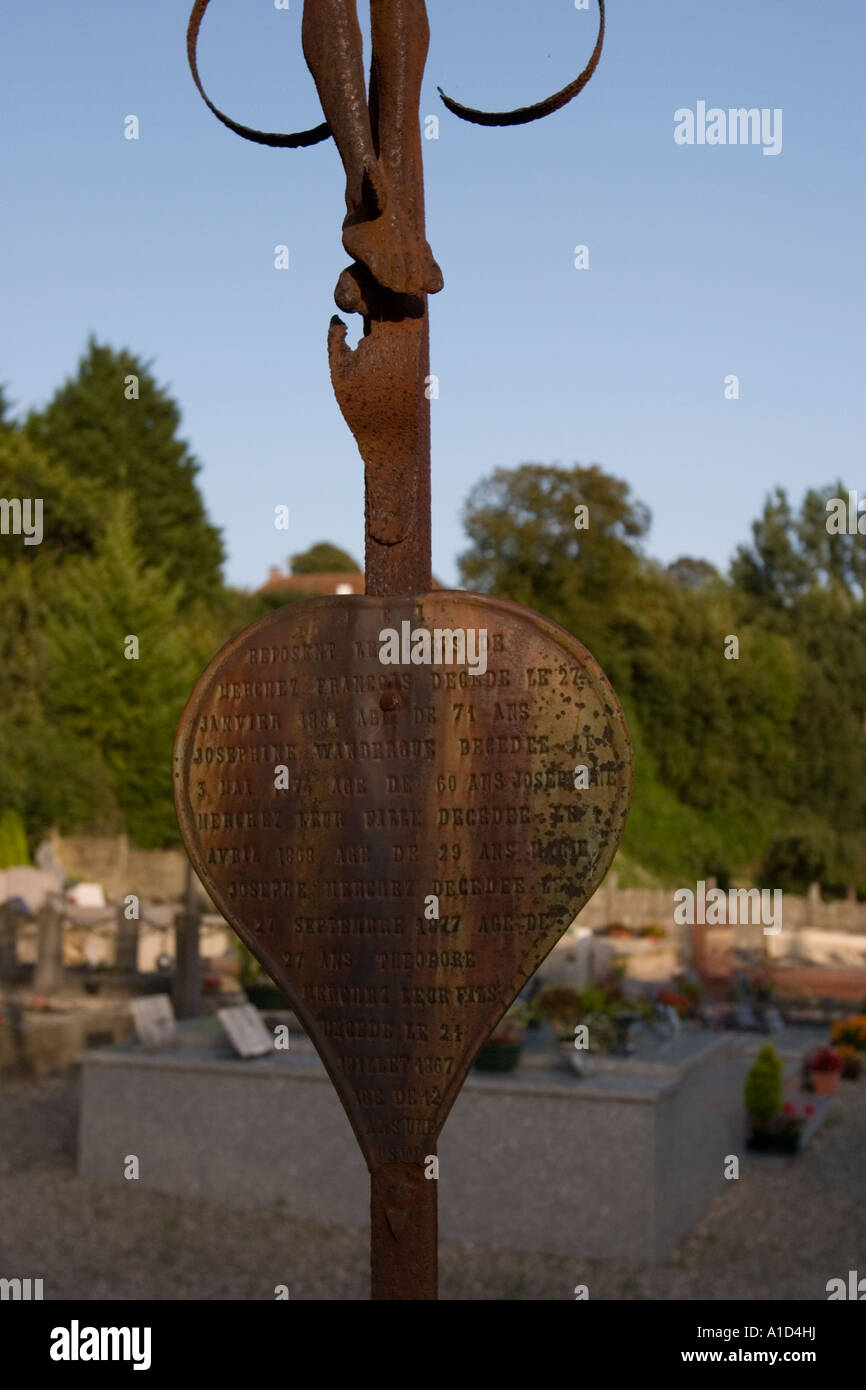 Corroded iron crucifix over grave in churchyard cemetry with figure of ...