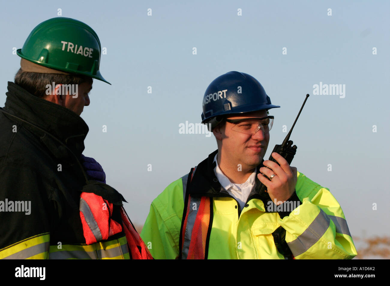 Tow fire fighter officers at an emergency scene talking on a radio ...