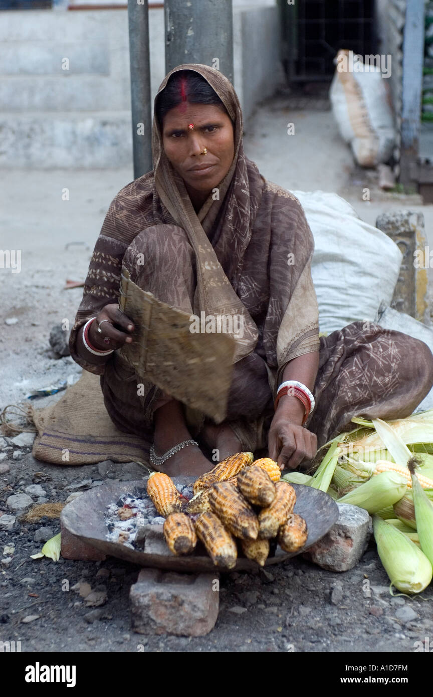 An Indian woman cooks corn on the street in Jaigon West Bengal Hills ...