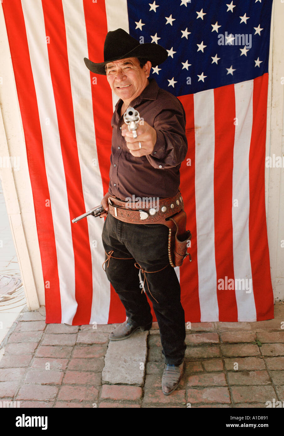 Cowboy with guns in front of flag pointing gun at camera Stock Photo ...