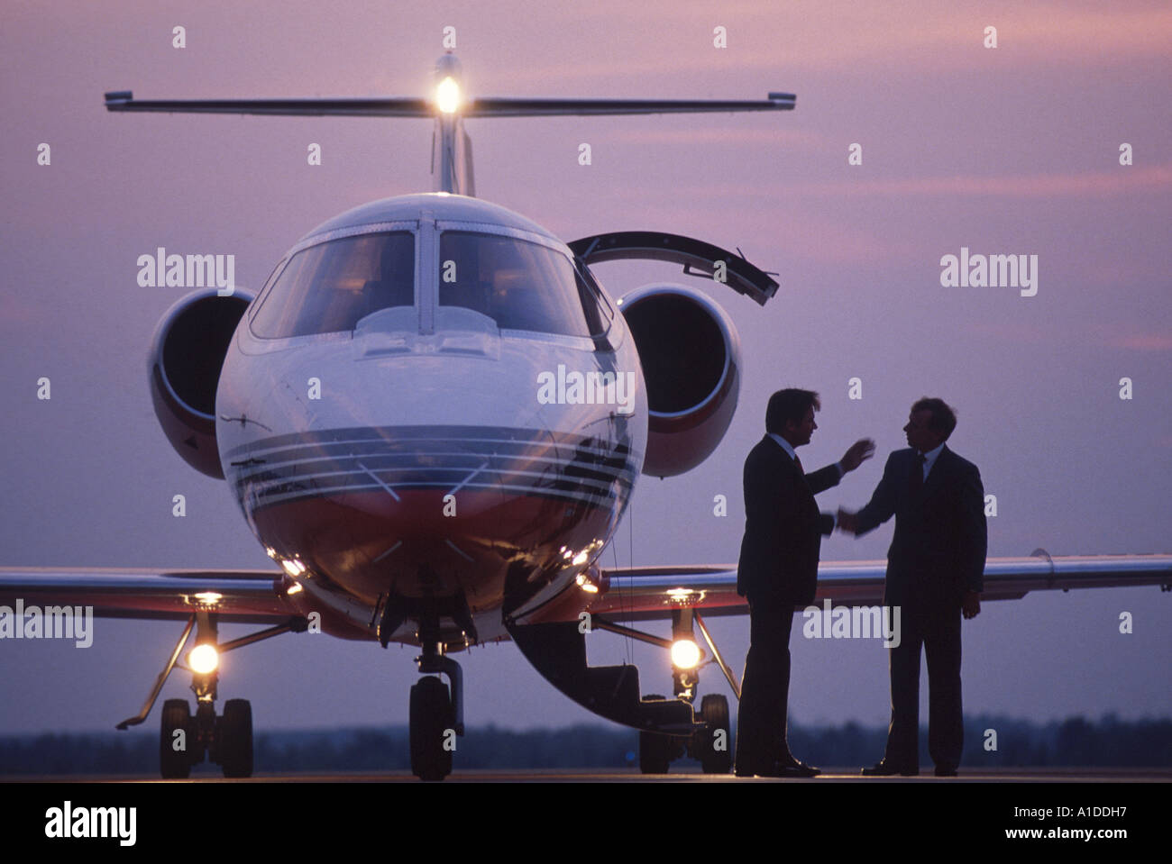 Two businessmen talking near an airplane Stock Photo - Alamy