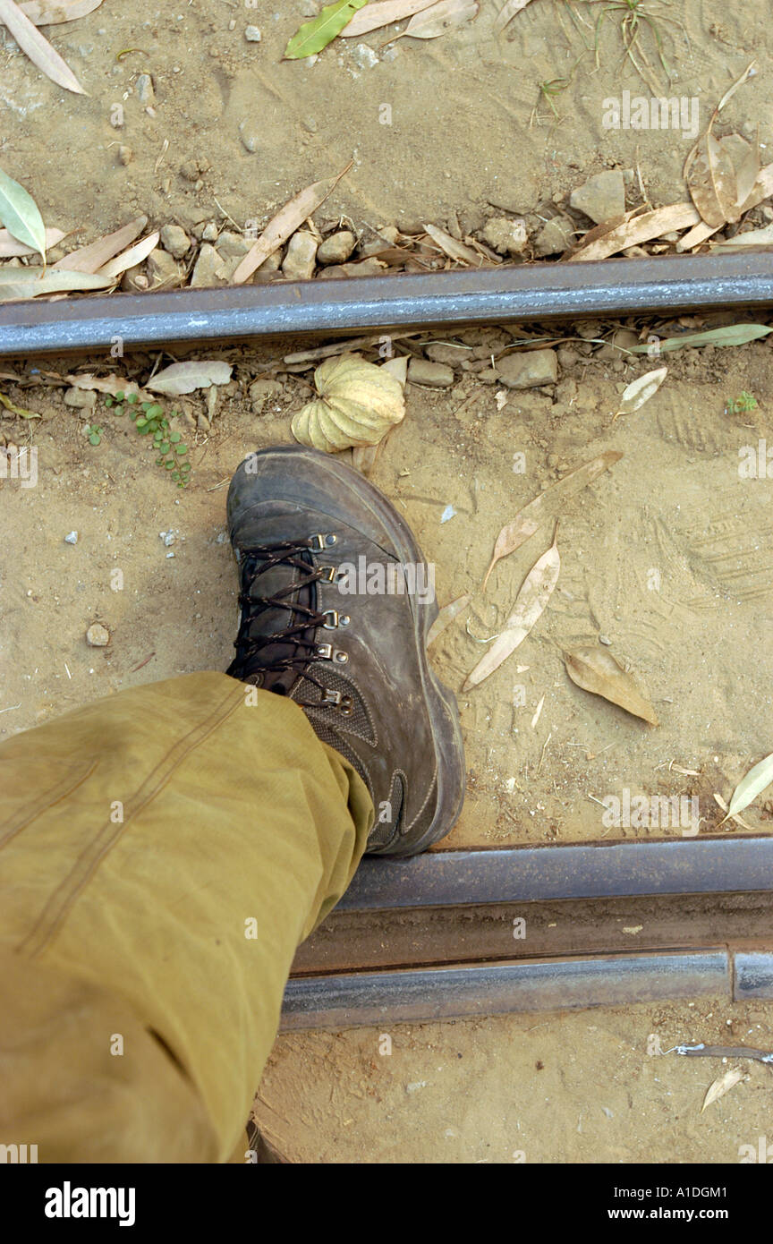 A leg with boots showing narrow gauge railway track Stock Photo - Alamy