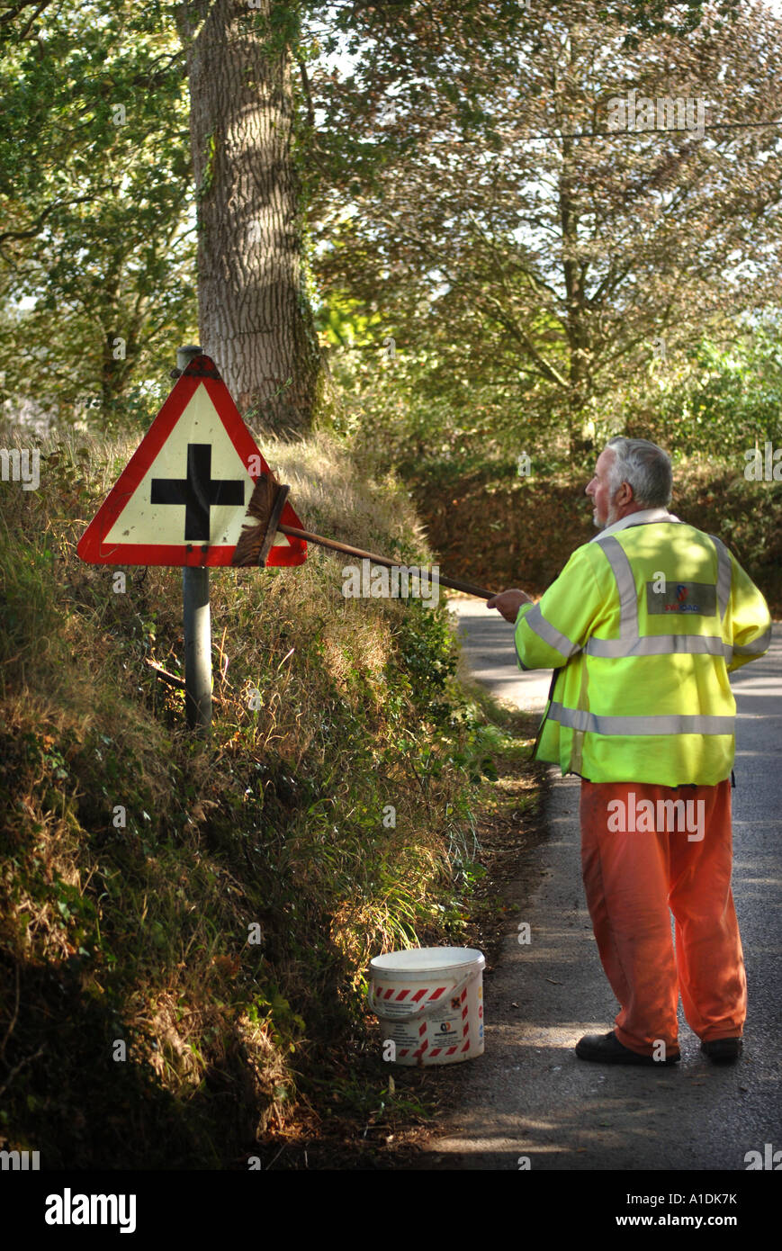 A HIGHWAYS WORKER CLEANING A CROSSROADS SIGN IN DEVON UK Stock Photo ...