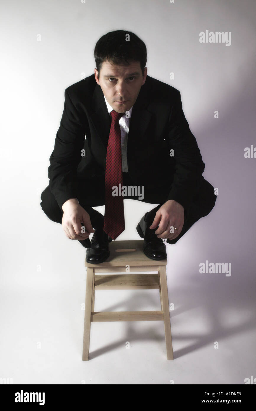 Business man crouched on stool hi-res stock photography and images - Alamy