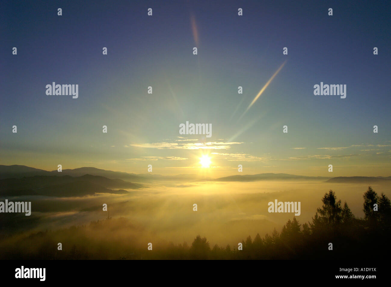 Sun rising above mountain ridge horizon into blue sky from yellow ...