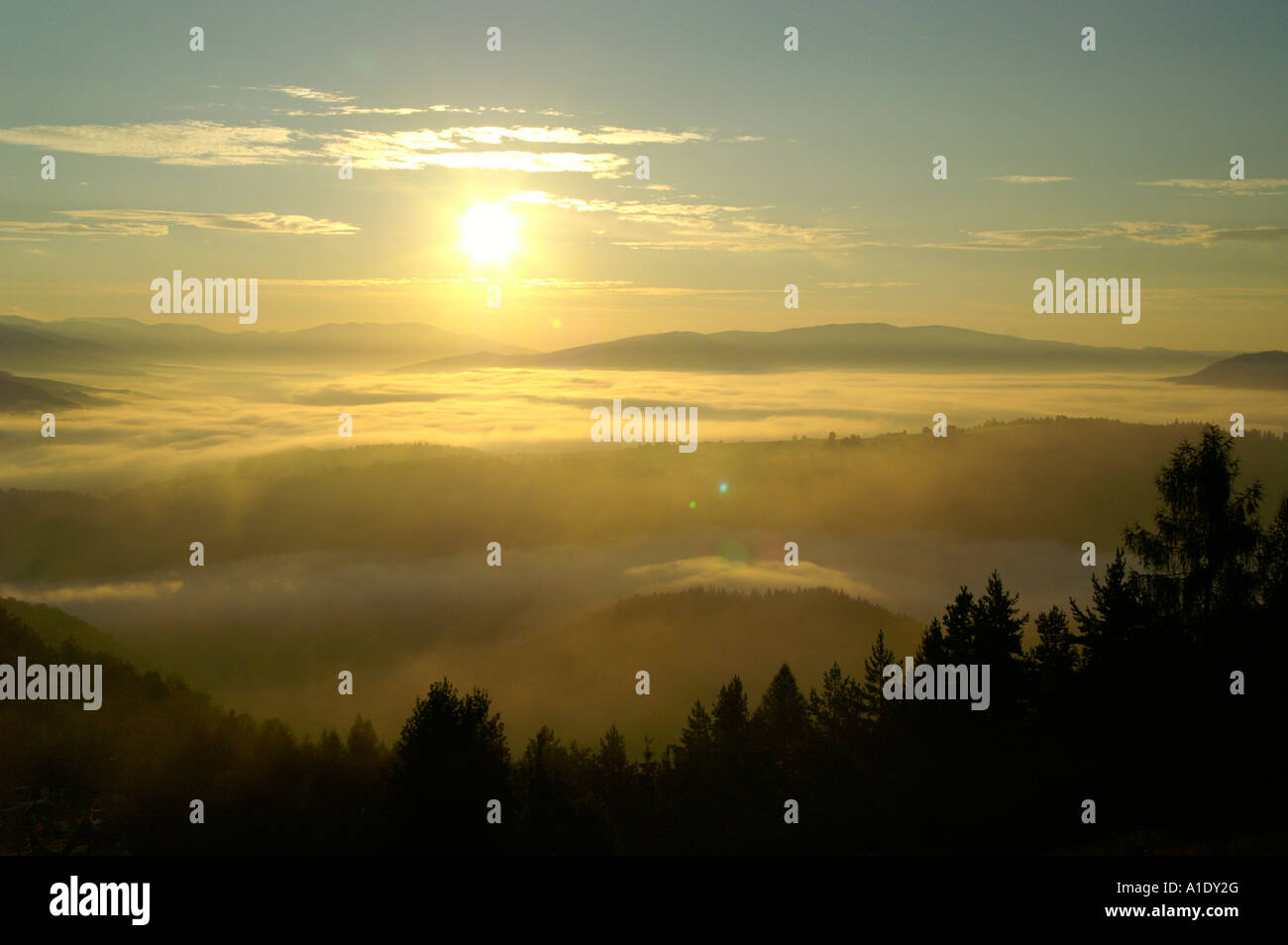 Sun rising above mountain ridge horizon from mist into blue sky, magic ...