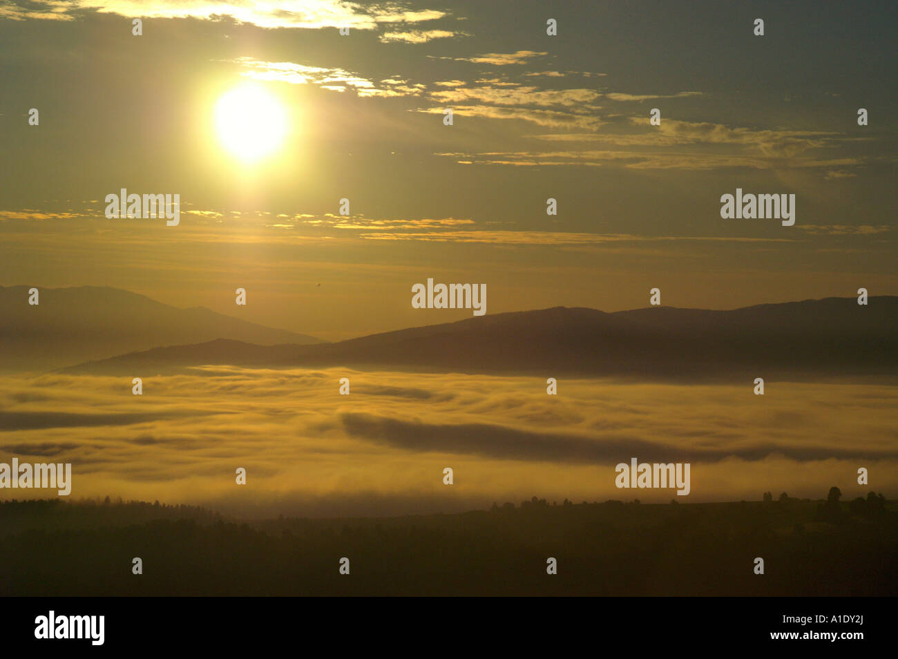 Sun rising above mountain ridge horizon from mist into blue sky, magic ...