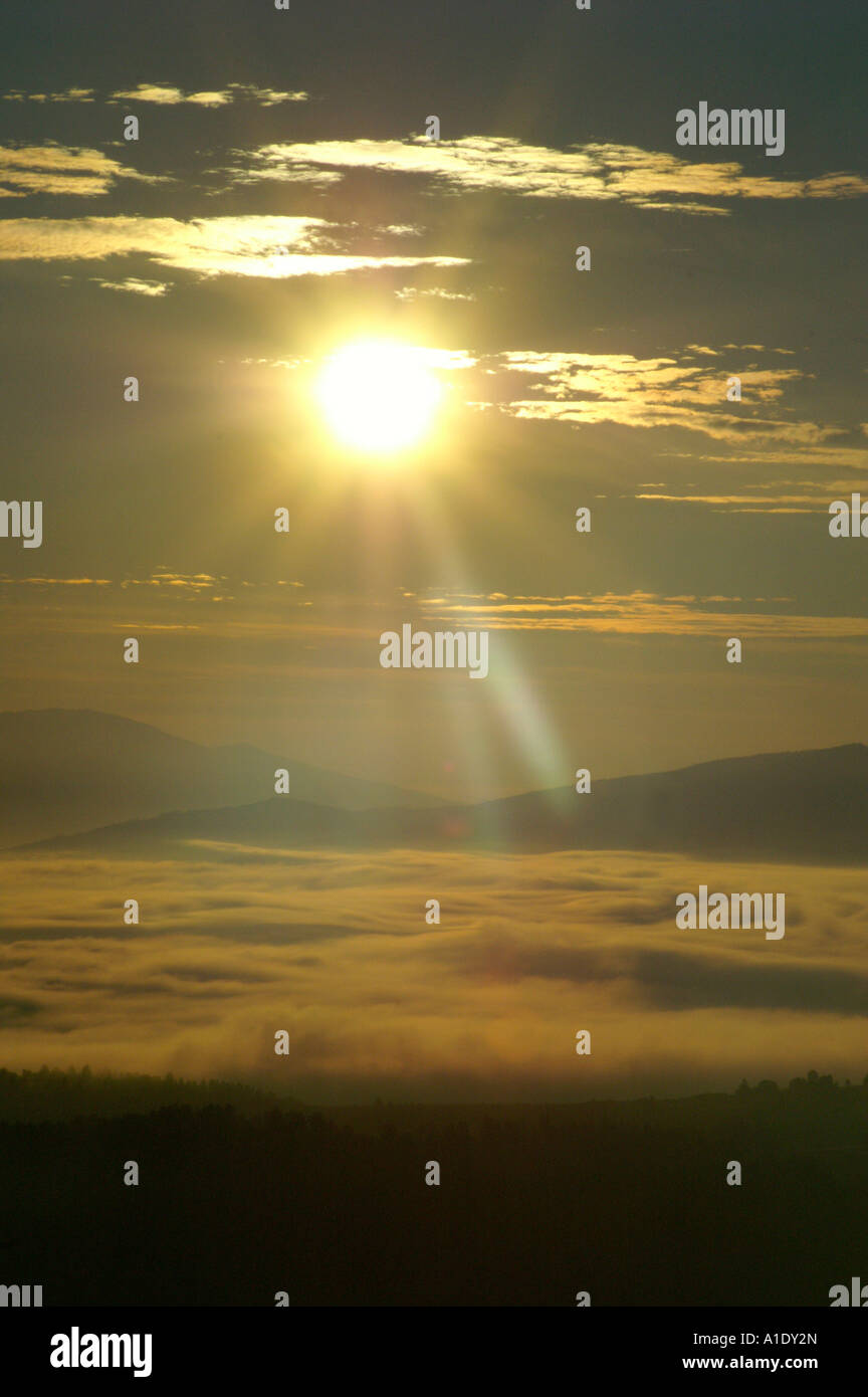 Sun rising above mountain ridge horizon from mist into blue sky, magic ...