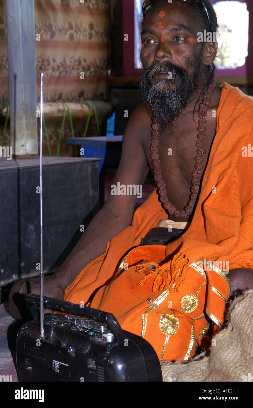 Old indian holy sadhu man in orange shawl listening radio in Parvati ...