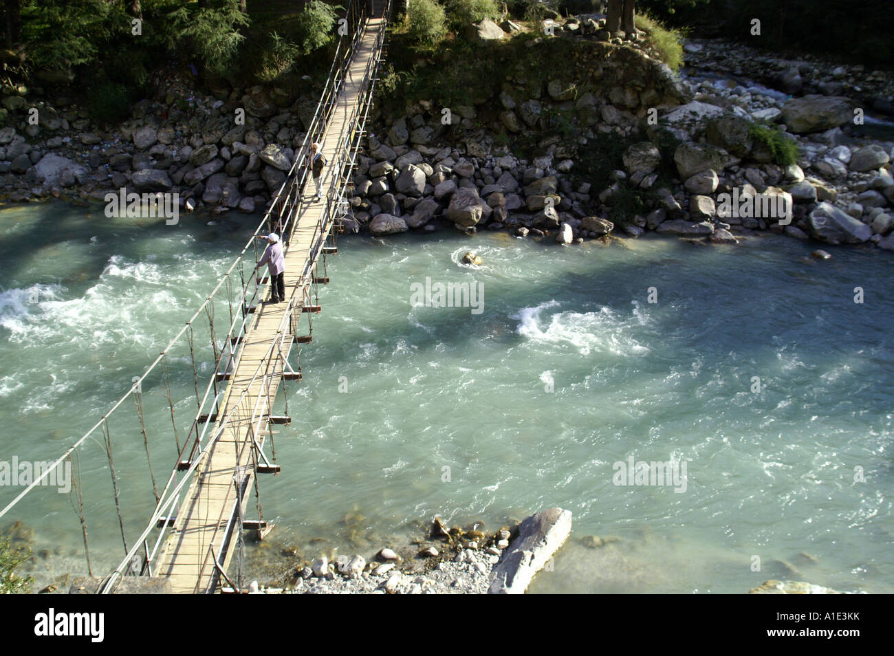 Narrow suspension bridge gangplank over swift River Parvati in Kasol ...