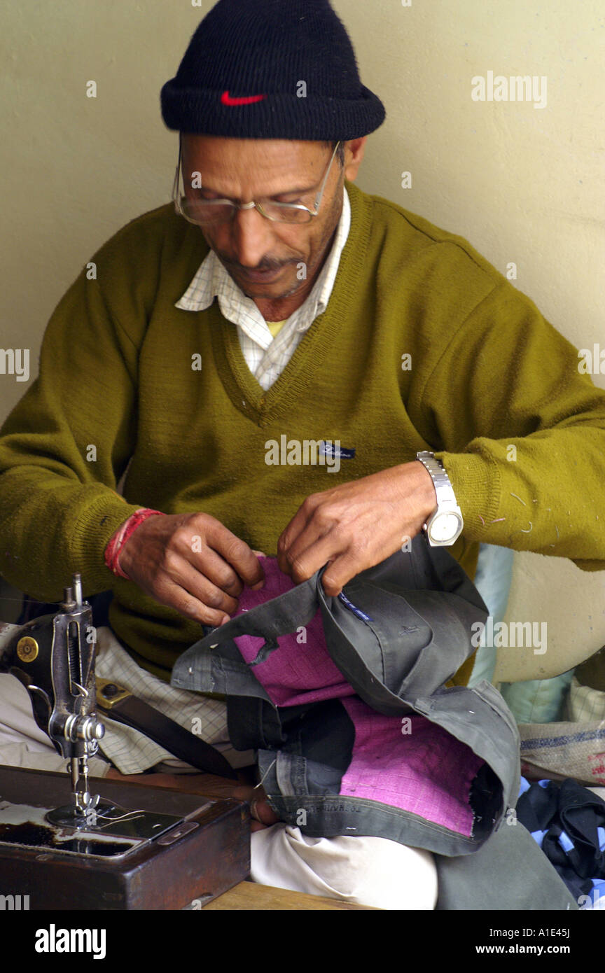 Old indian man tailor stitching trousers on archaic sewing machine ...