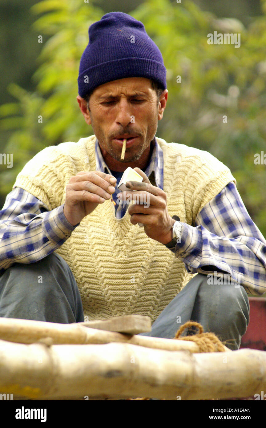 Old indian man with blue ski woolen cap smoking beedee cigarette on ...