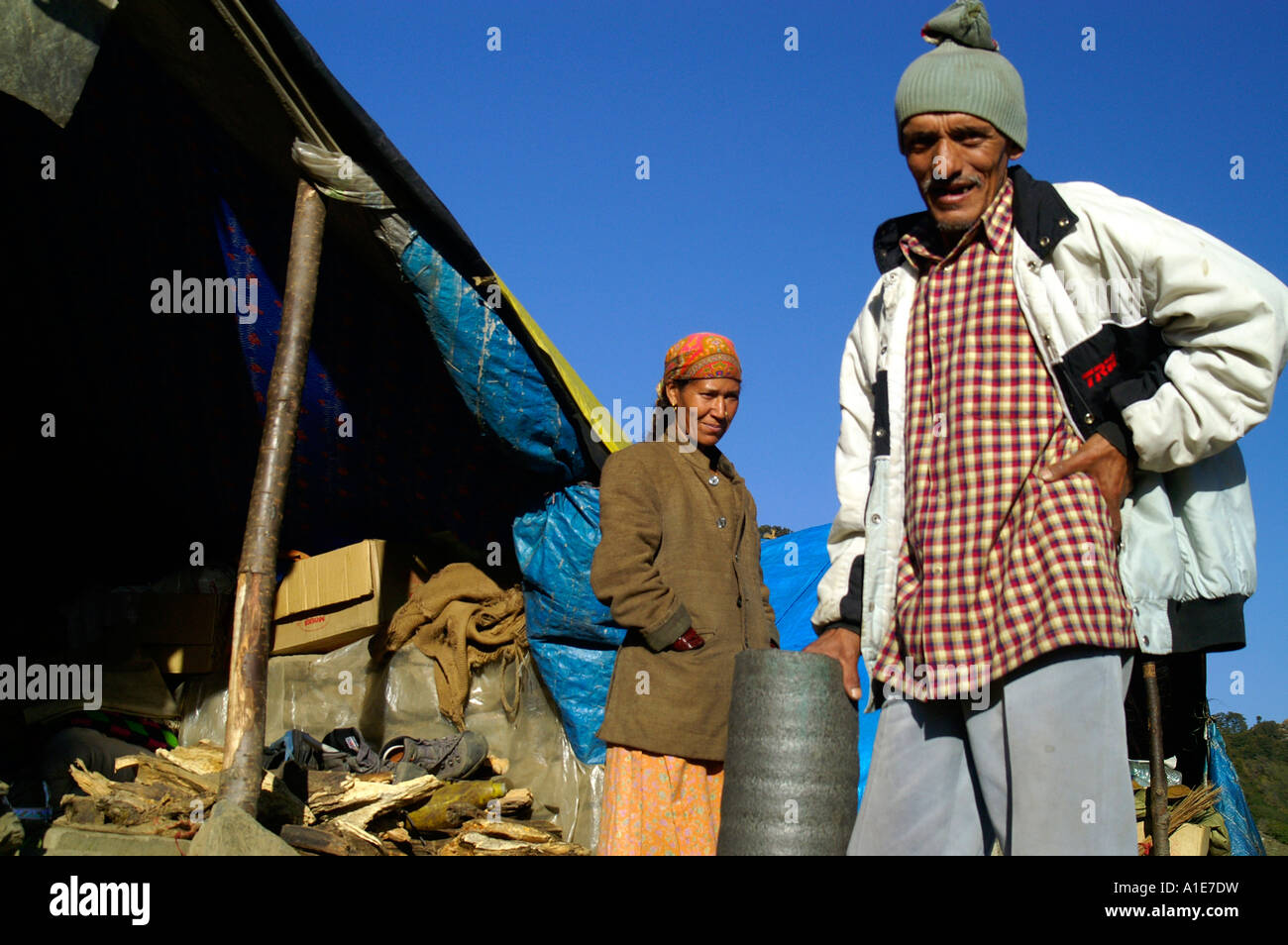 Old indian highlander man standing with his wife in front of shelter in ...
