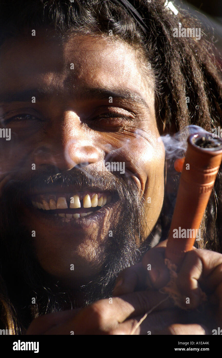 Face portrait smiling sadhu indian man with hashish pipe smoking and ...