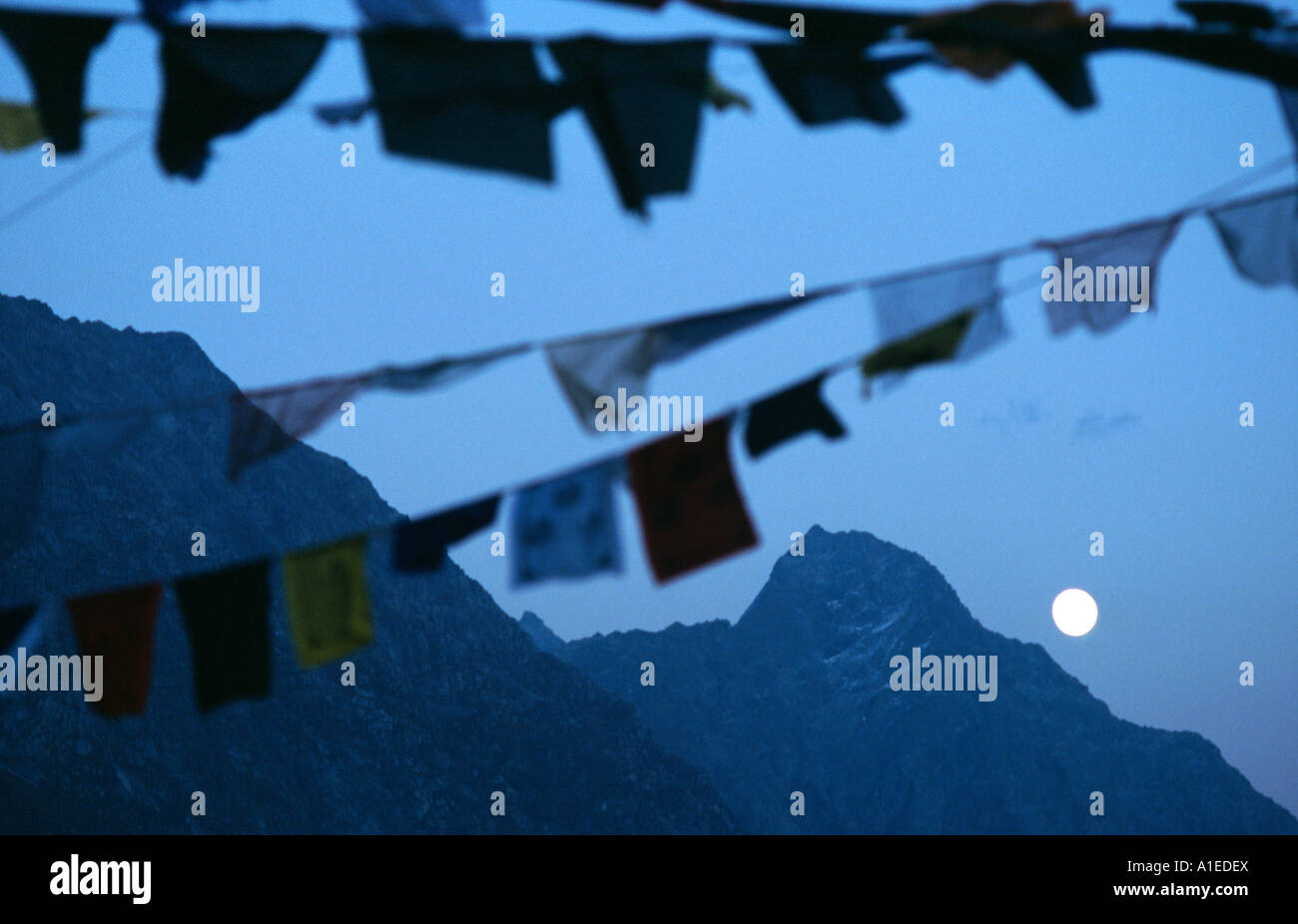 Tibetan prayer flags fluttering over a peak in the Indian Himalayas ...
