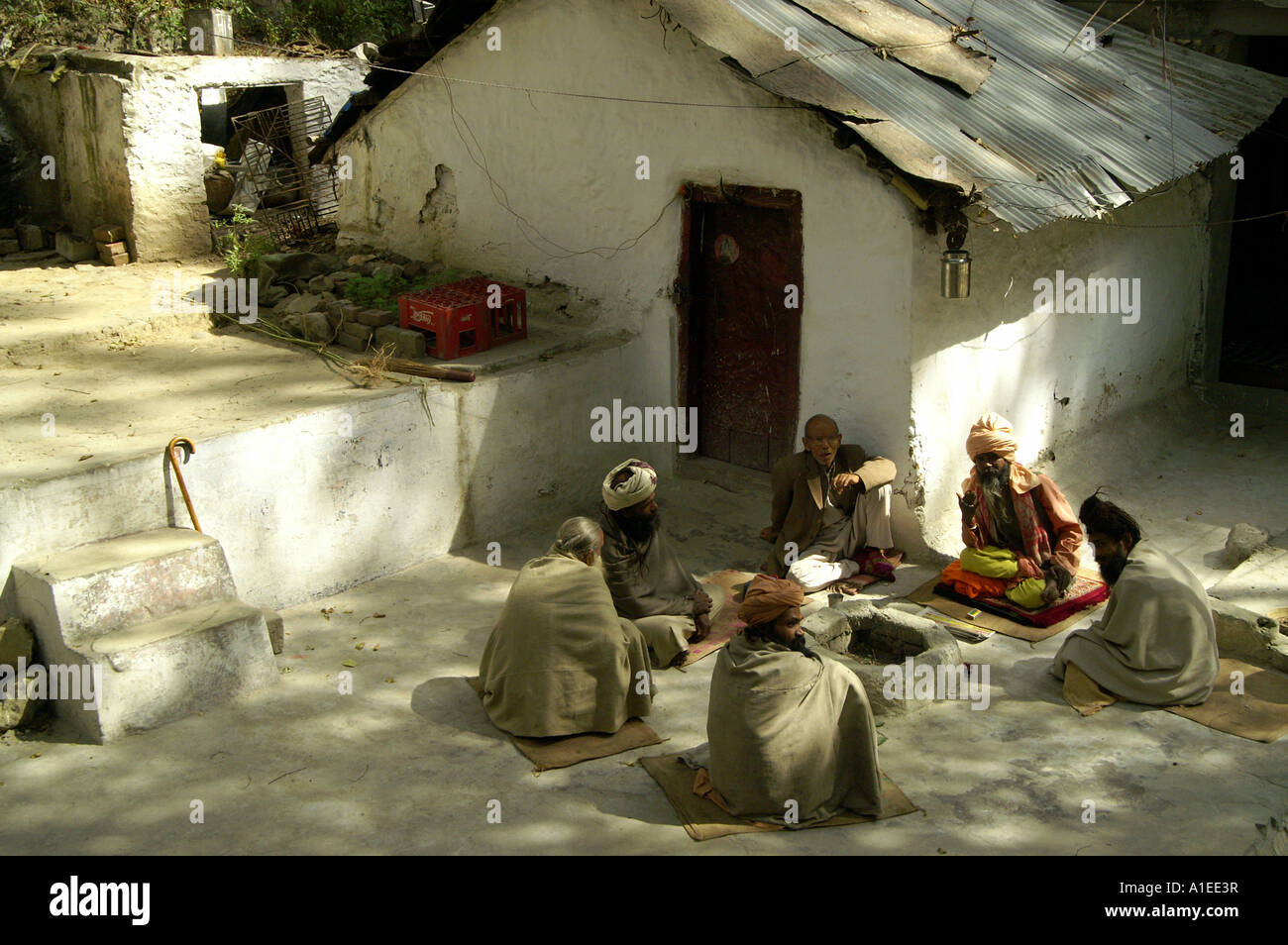 Indian sadhus holy men sitting and discussing on terrace of white house ...