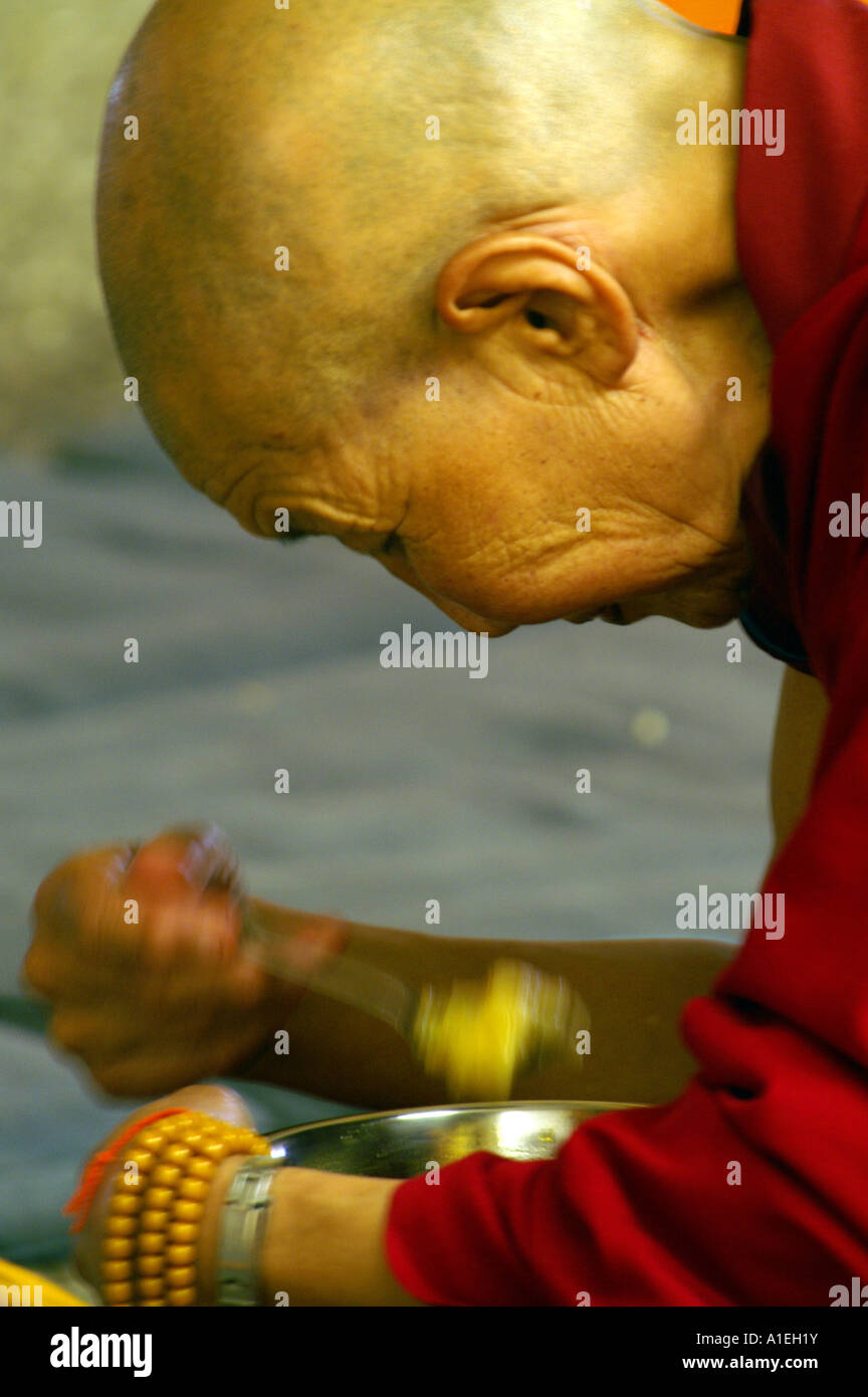 Female buddhist monk eating her lunch soup from stainless steel plate ...