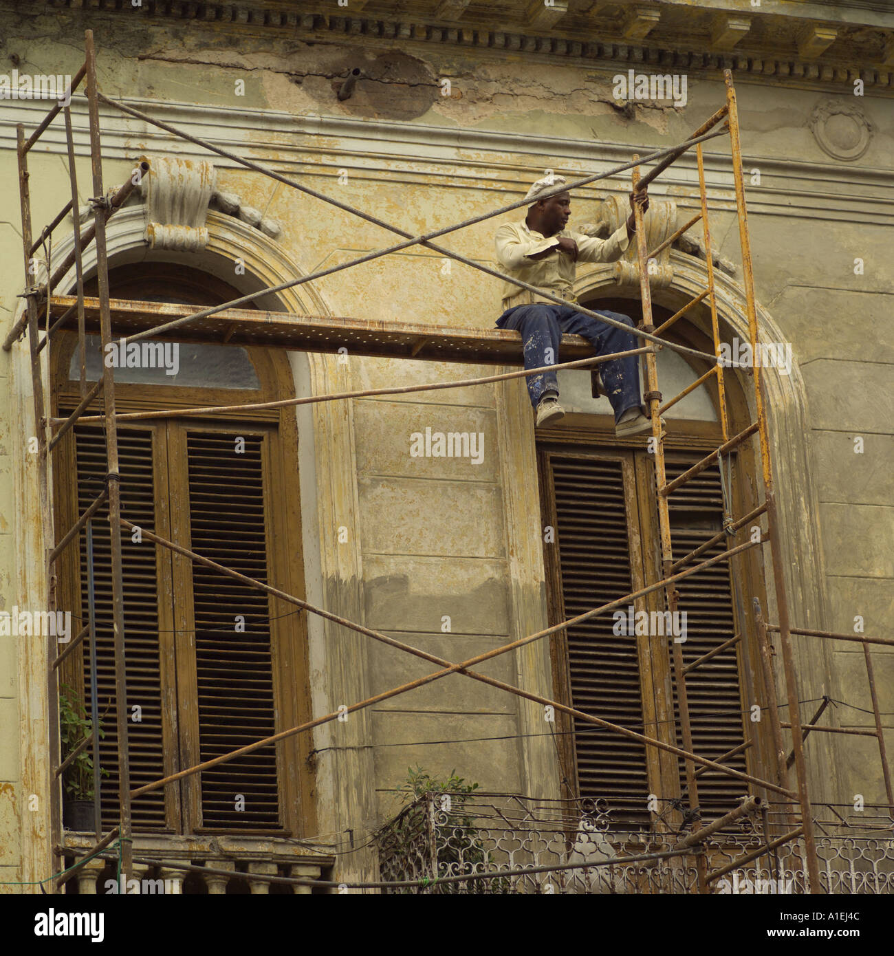 Low angle view of a man sitting on a scaffolding of a building Havana ...
