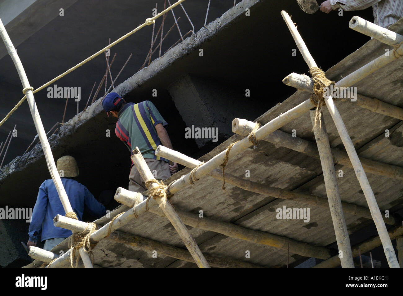 Indian plasters plastering concrete wall on platform of bamboo ...