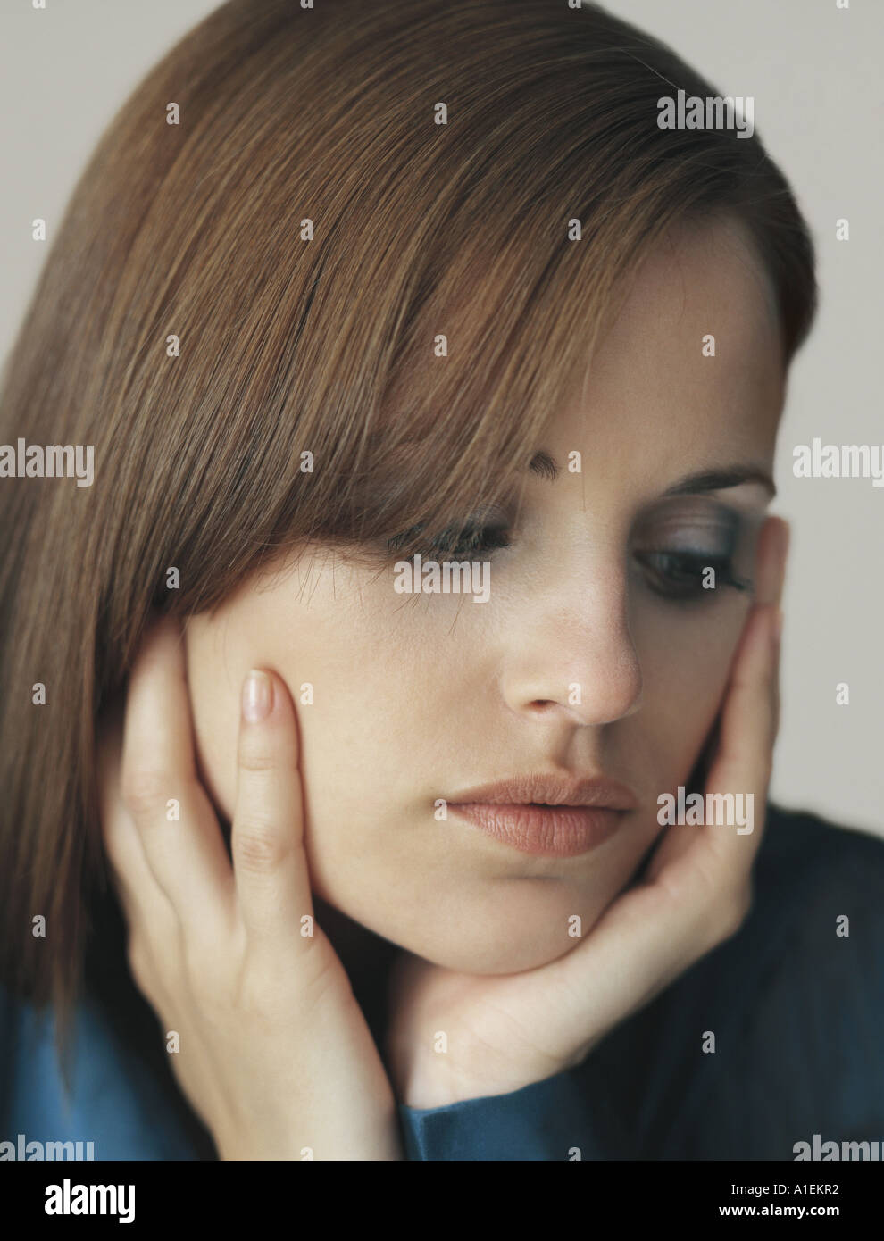 Woman holding face in hands, looking down, portrait Stock Photo - Alamy