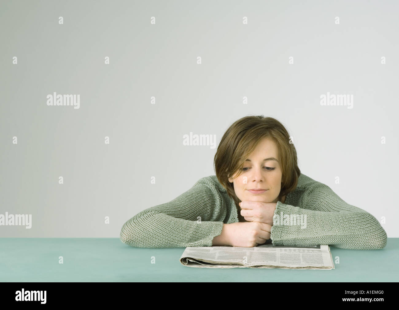 Young woman leaning on table, reading newspaper Stock Photo - Alamy