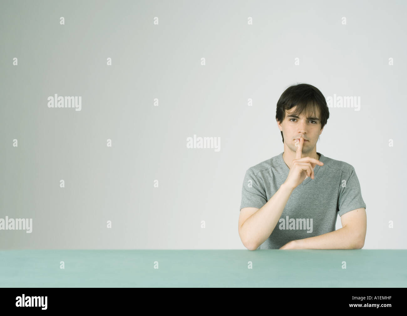 Young man with fingers over lips Stock Photo - Alamy