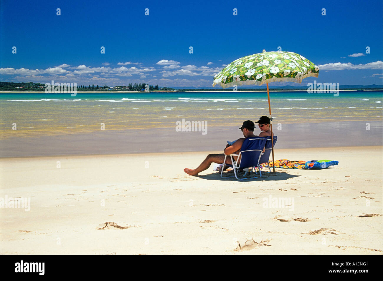Young couple relaxing under a beach umbrella, Australia Stock Photo - Alamy