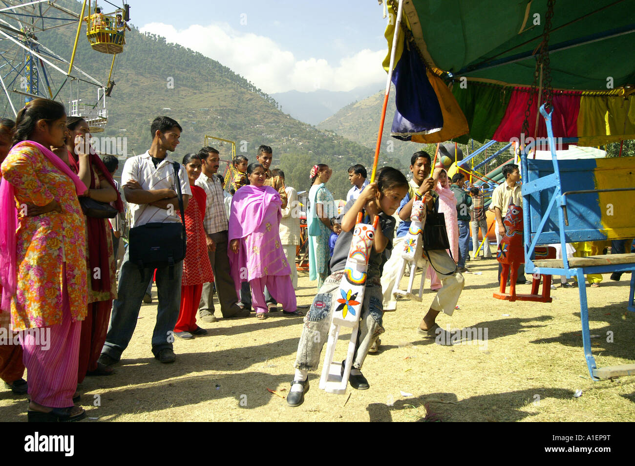 Crowds waiting next to Indian merry go round horse at Dussehra festival ...