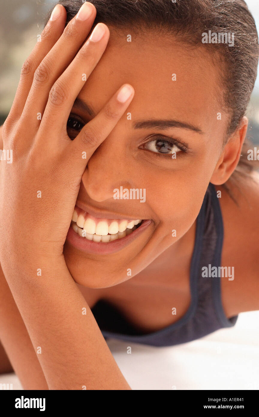 Smiling young woman partially covering face Stock Photo - Alamy