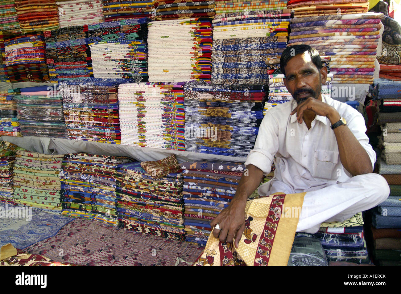 Owner of textile stall sitting in front of goods at Dussehra fair ...