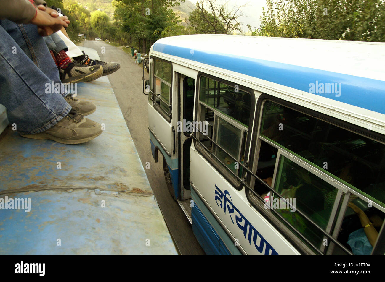 Passengers travelling on roof of overfull bus meeting another bus ...