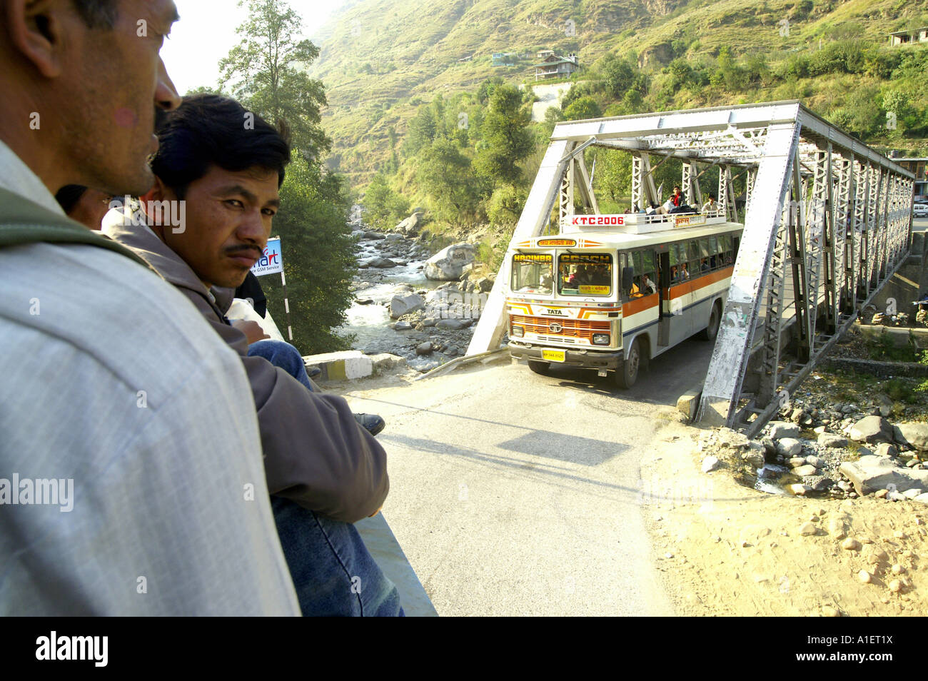 Passengers travelling on roof of overfull bus entering single track ...