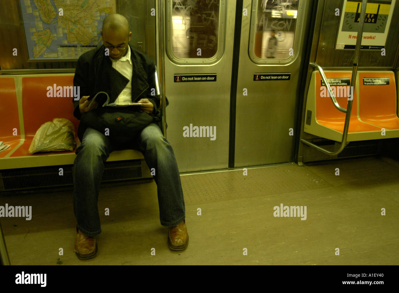 A man reading a magazine on a subway train in New York Stock Photo - Alamy