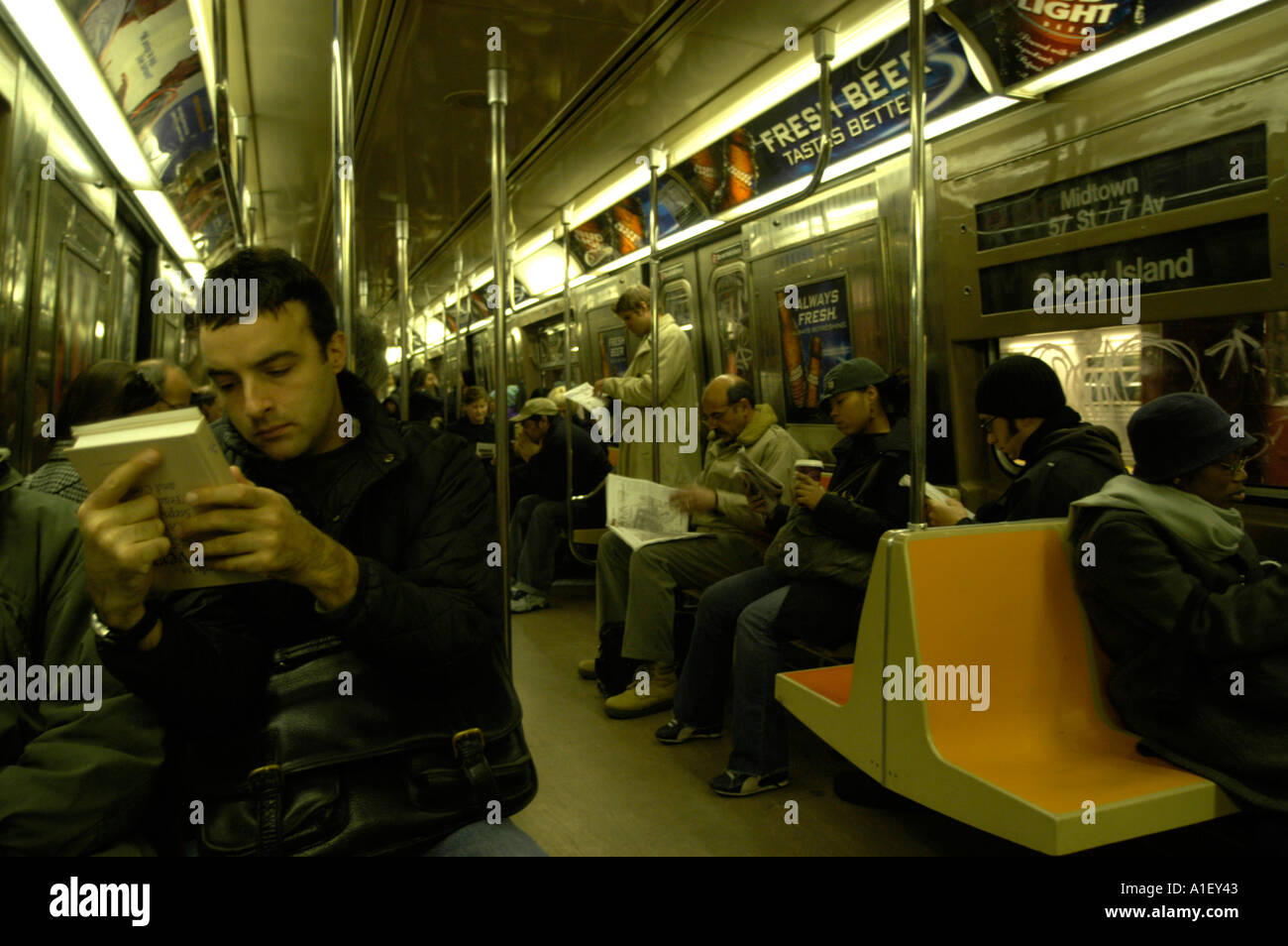 A man reading a book on a busy subway train in New York Stock Photo - Alamy