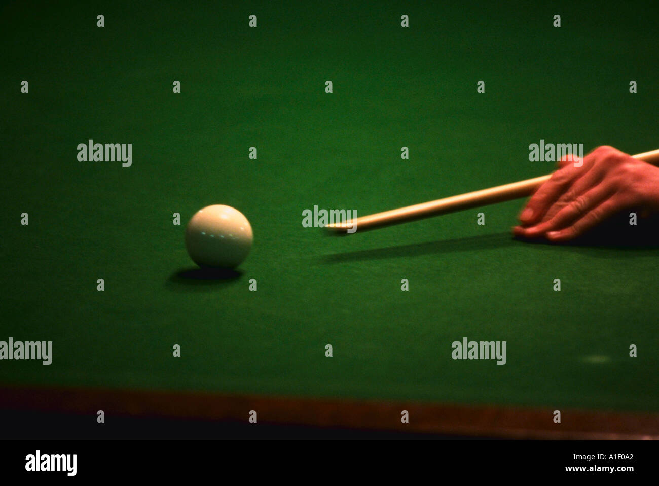 Hand holding billiard cue on pool table pointing at white cue ball ...