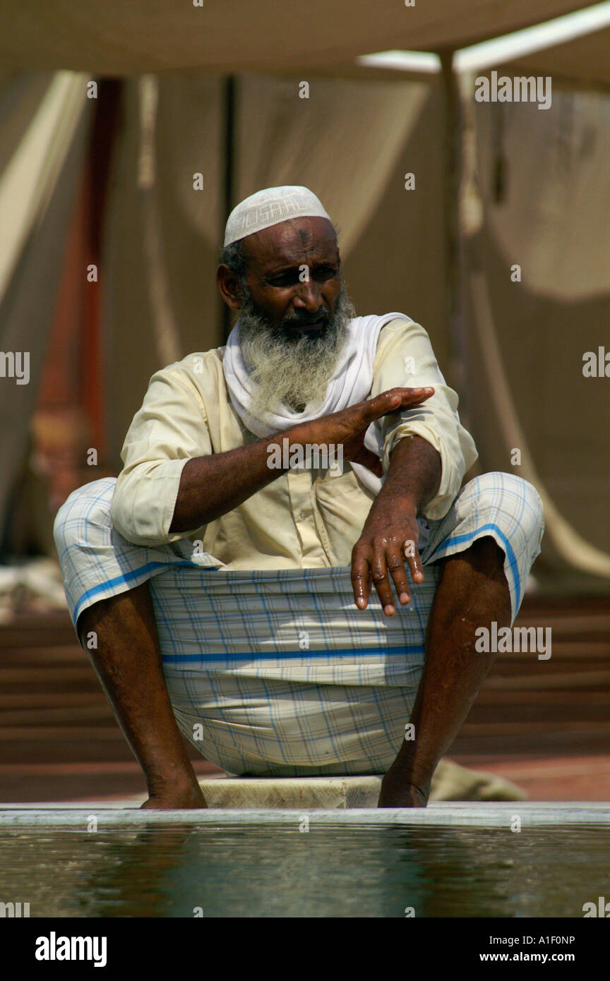 Old religious Muslim man performing ritual bath in Jama Masjid mosque ...