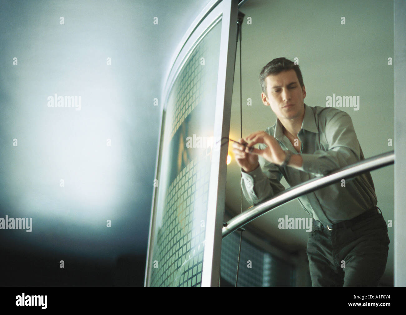Businessman leaning on rail, low angle view Stock Photo - Alamy