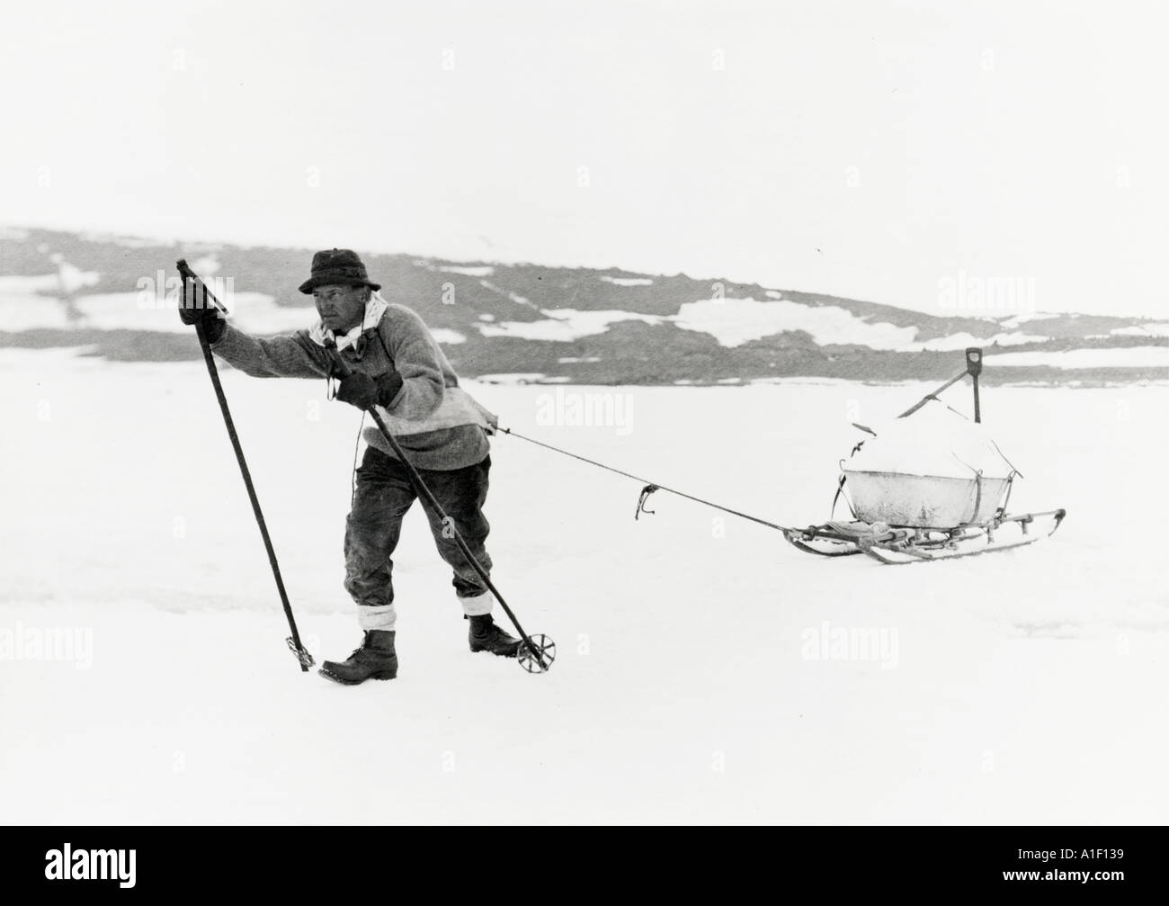 Drake amember of the crew pulls sledge carrying blocks of ice to melt ...