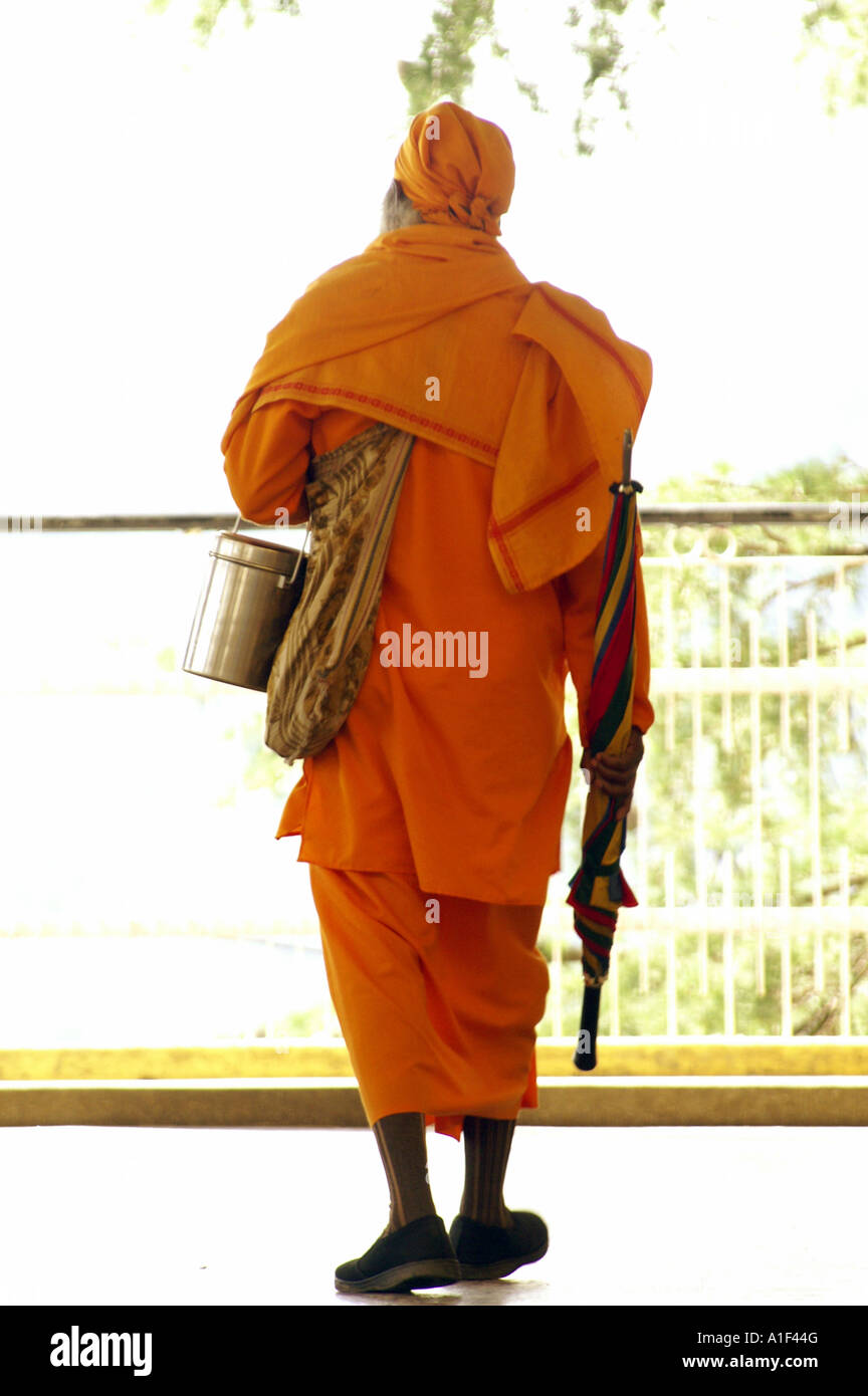 Hinduistic sadhu in orange robe walking, at Namgyal monastery terrace ...