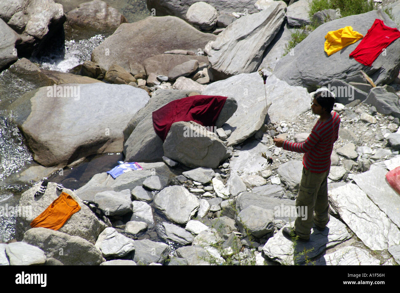 Indian boy juggling in water stream standing on boulder Stock Photo - Alamy