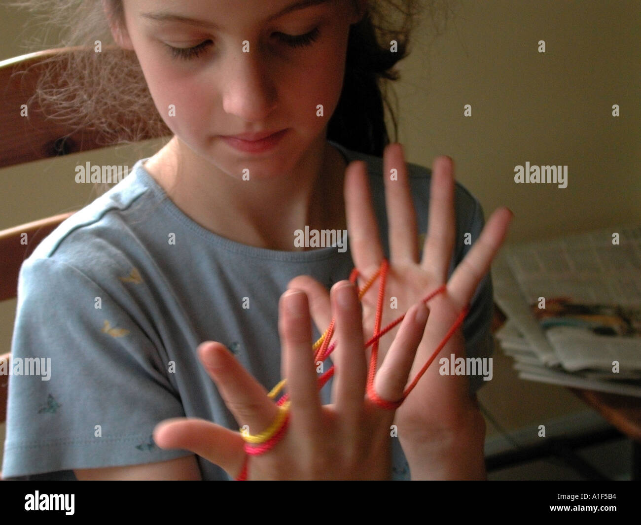 An eight year old girl pacticing string figures Stock Photo - Alamy