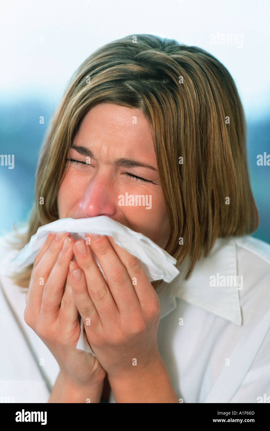 Woman sneezing into tissue Stock Photo - Alamy