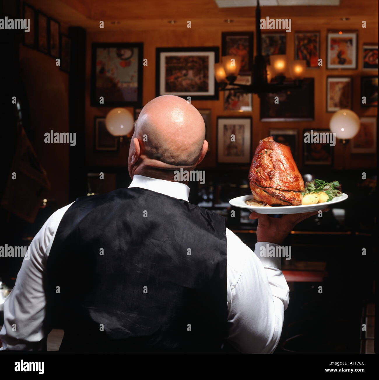 bold, old waiter with a crease neck, serving a dish of pigs trotters ...