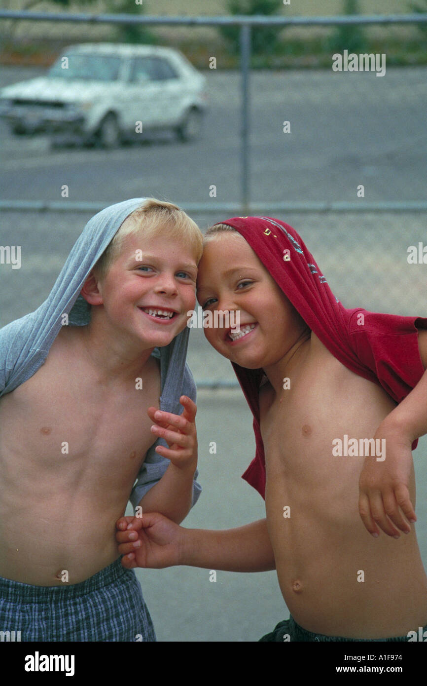 two young boys goofing around outside with their shirts pulled up over ...