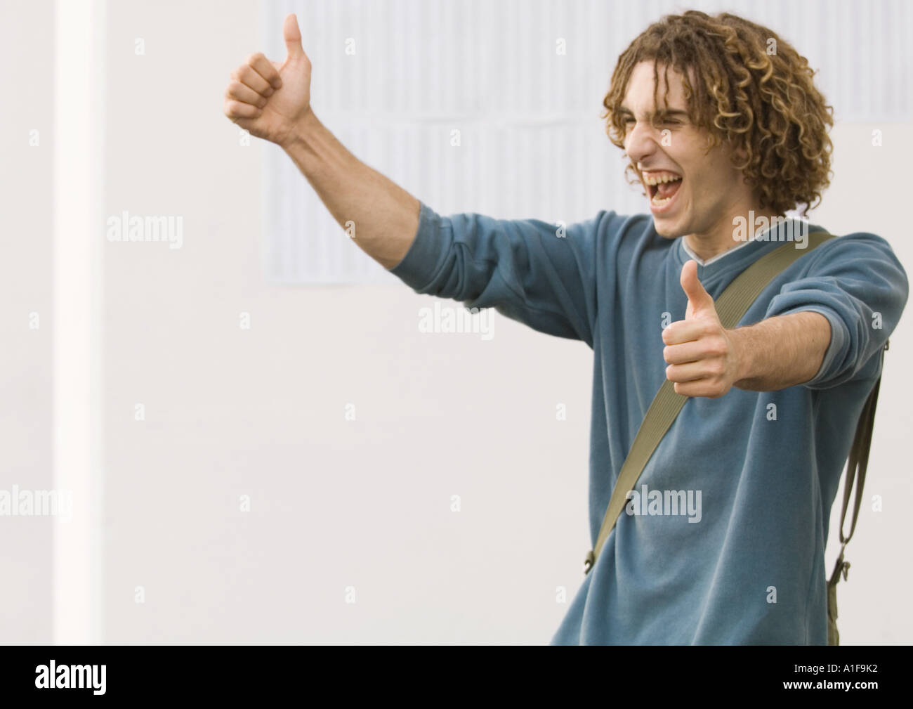 Student making thumbs up sign and shouting with joy, in front of ...