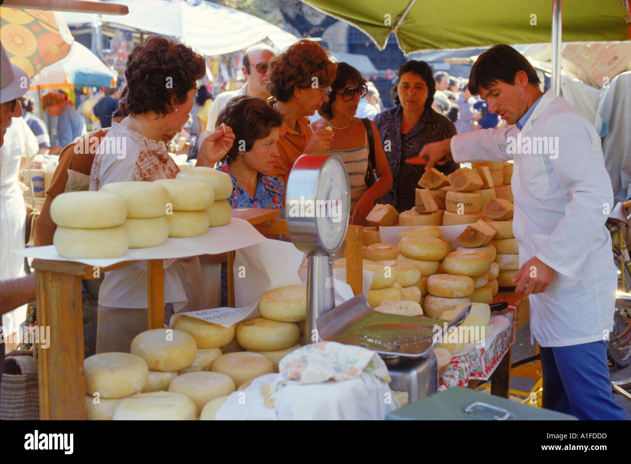 Shoppers tasting cheeses at a cheese stall in the market in the town of ...