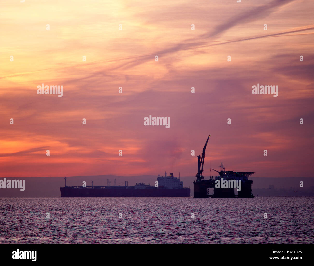 Ship by oil rig at sunset Stock Photo - Alamy