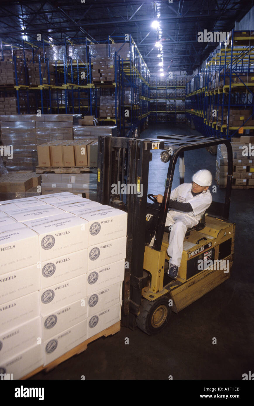 A worker using a forklift to move a pallet of cheese being stored in a ...